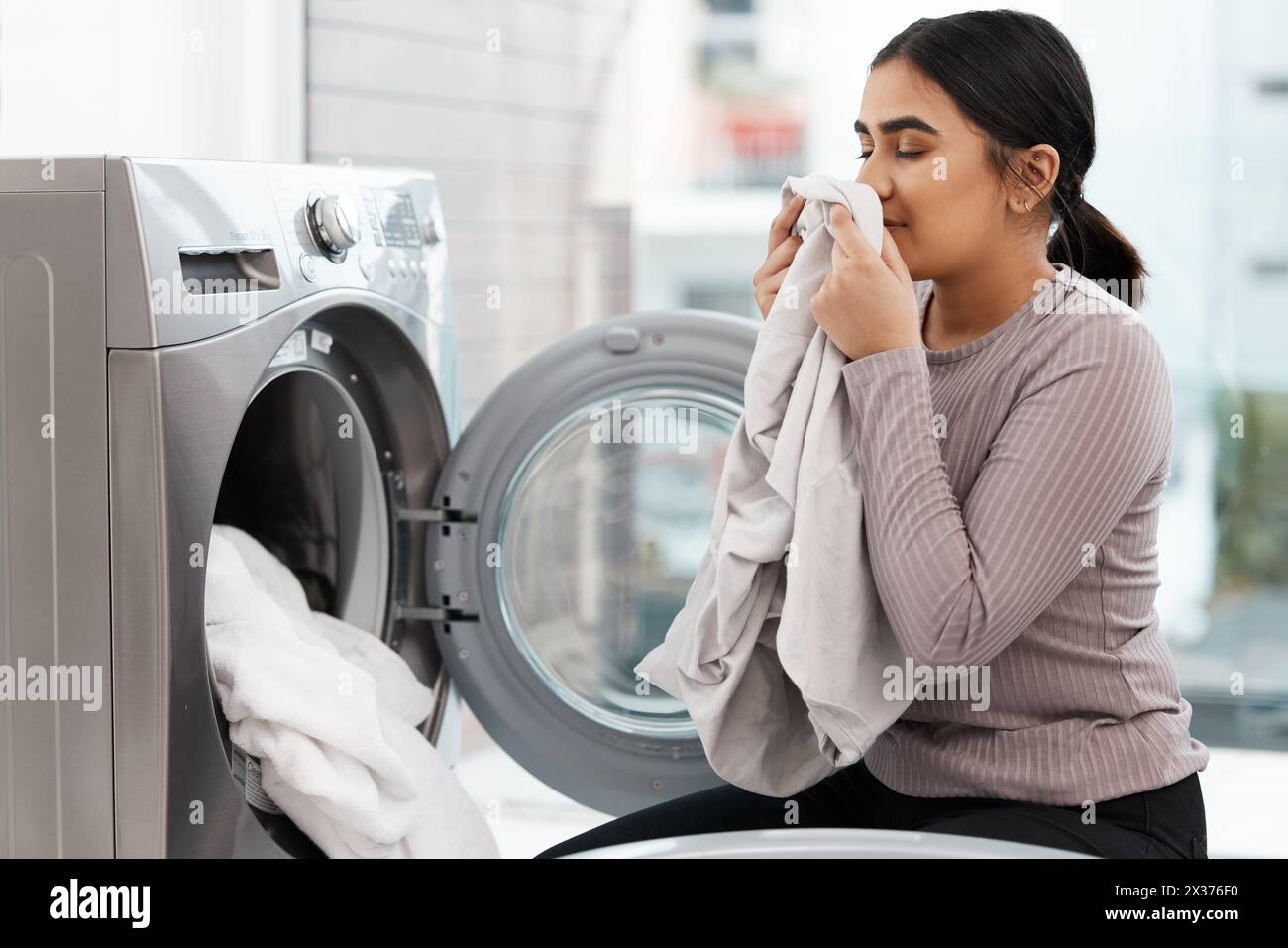 Laundry, fresh scent and washing machine with woman smelling clothes in ...