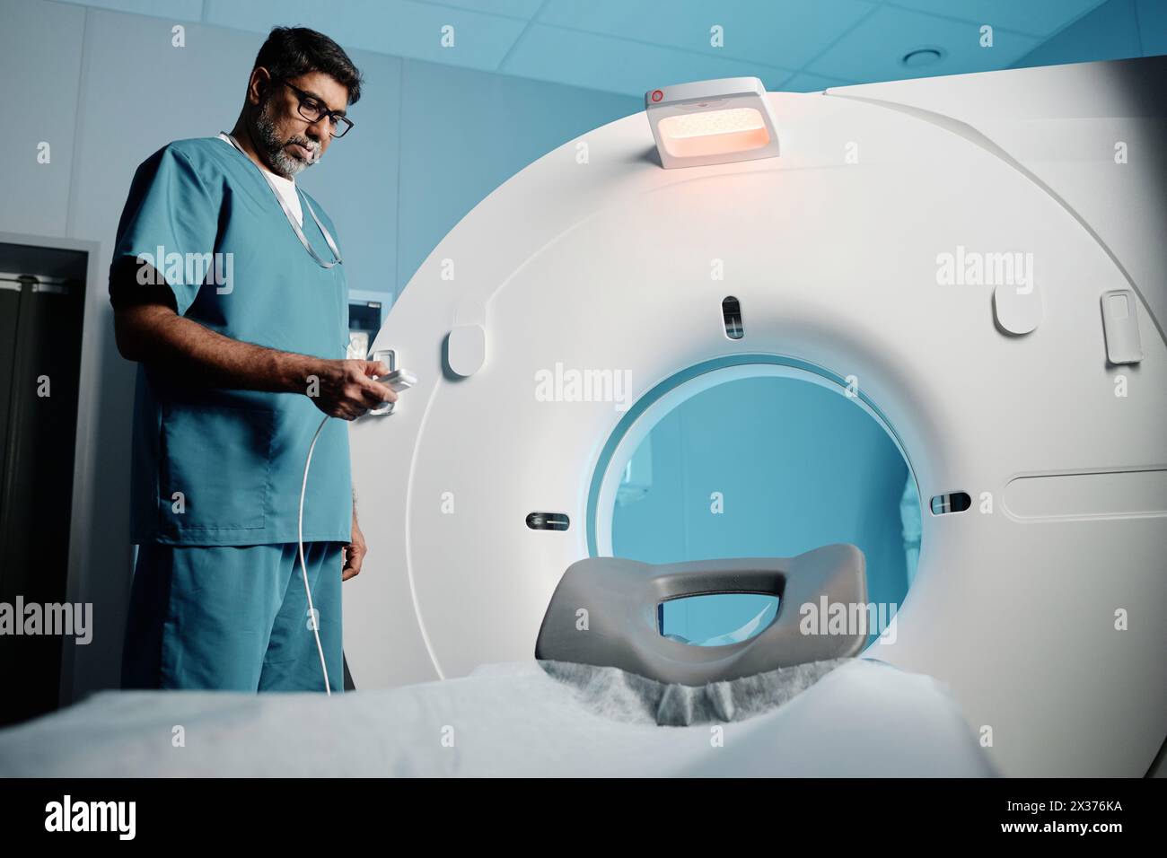 Medium long shot of biracial doctor adjusting MRI scanner settings for ...