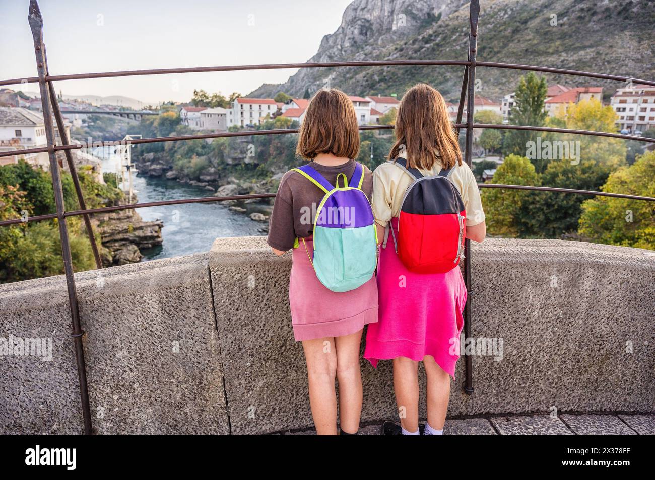 Twin girls standing on famous Mostar bridge, looking at Mostar town and ...