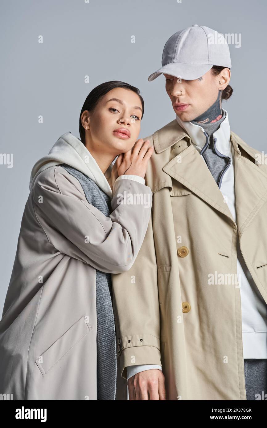 A young stylish couple stands confidently next to each other in trench ...