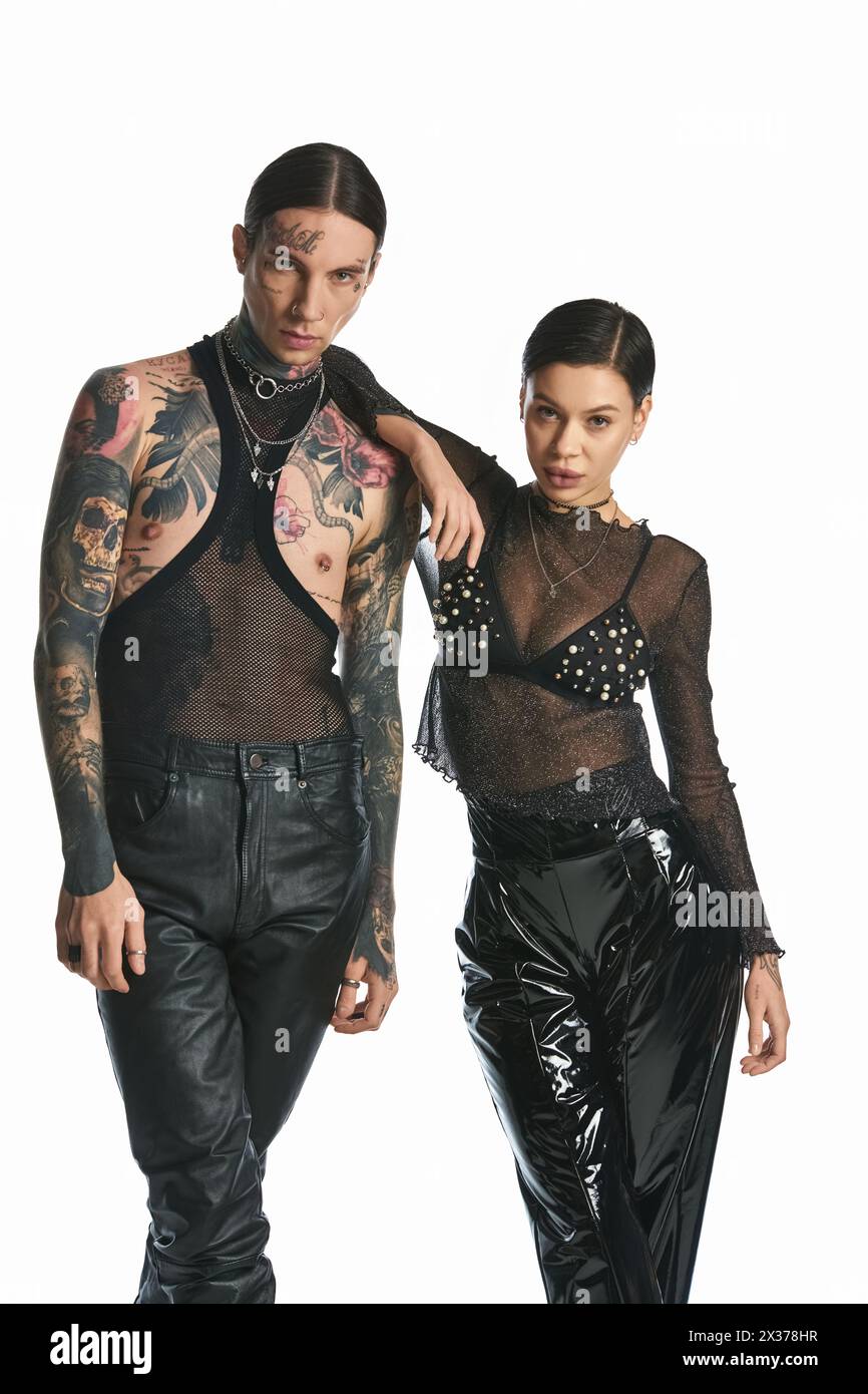 A young, stylish man and woman with tattoos stand together in a studio ...