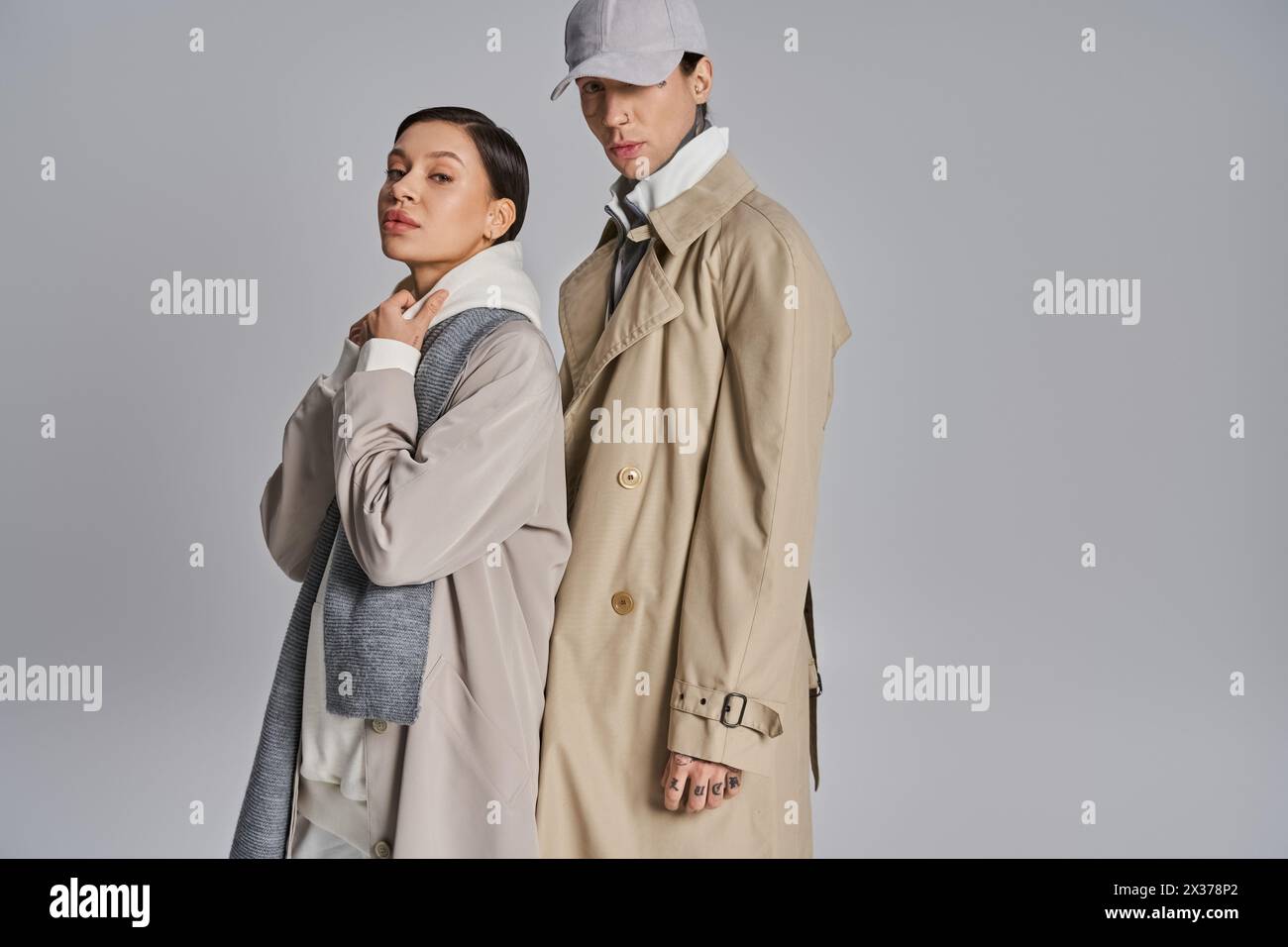 A young stylish couple in trench coats standing next to each other in a ...