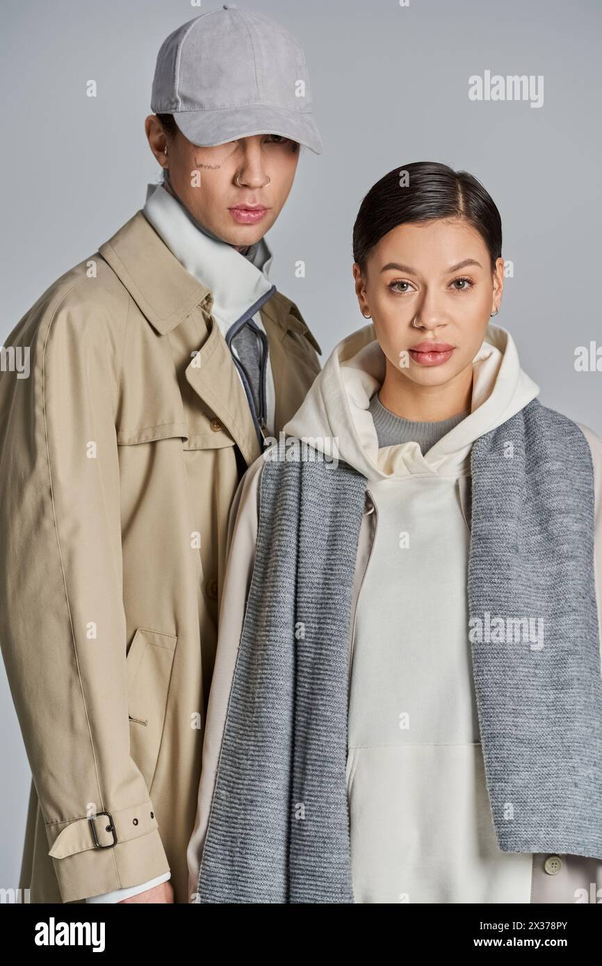 A young stylish couple wearing trench coats standing together in a ...