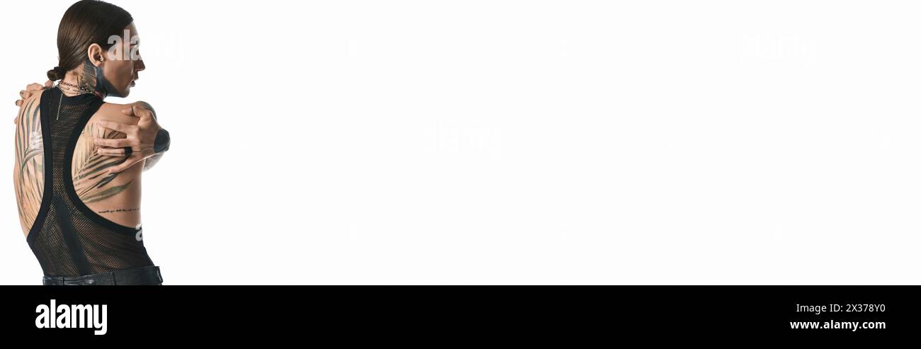 A young man with intricate tattoos on his back, standing confidently in ...