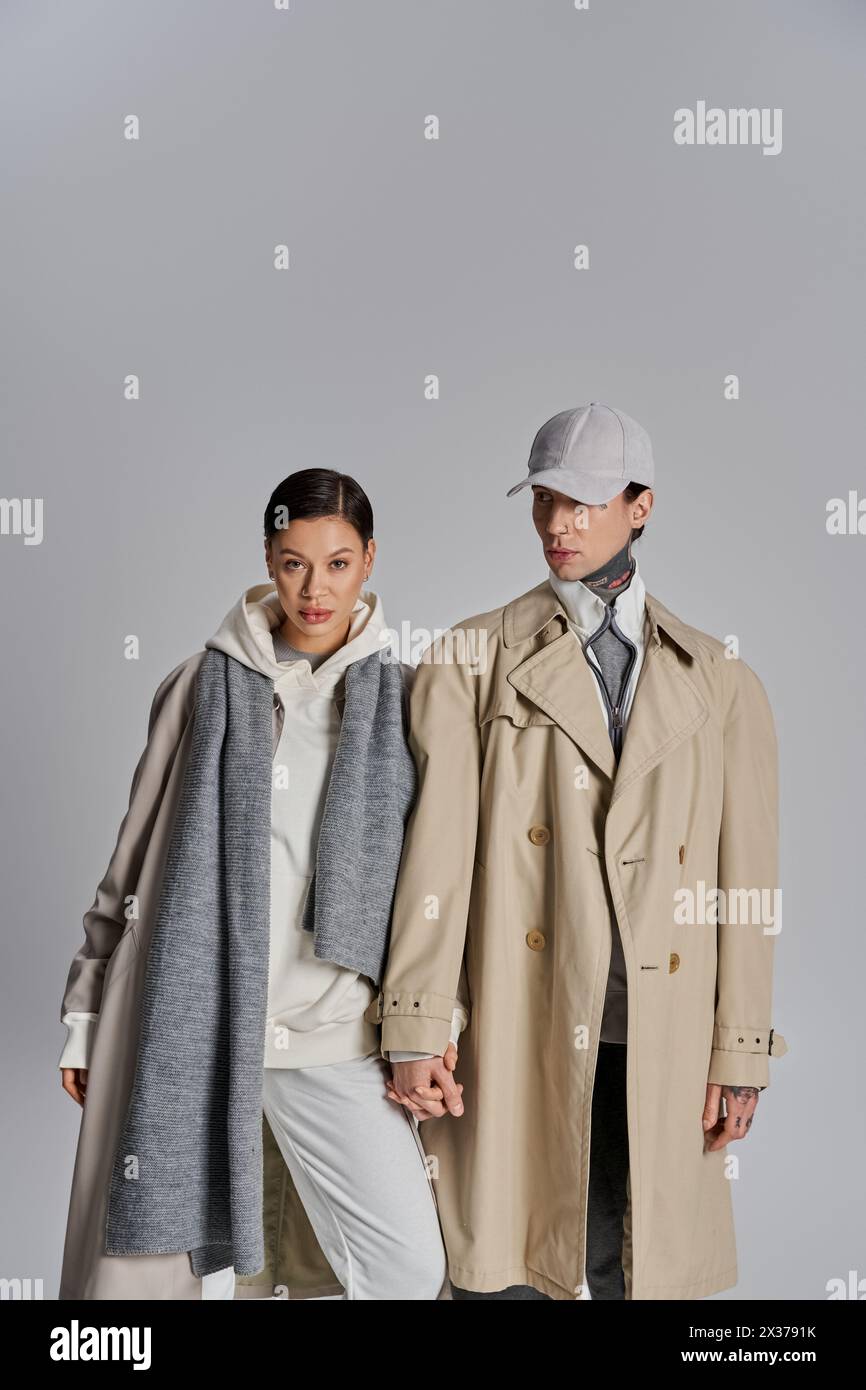 A young stylish couple in trench coats stands gracefully next to each ...