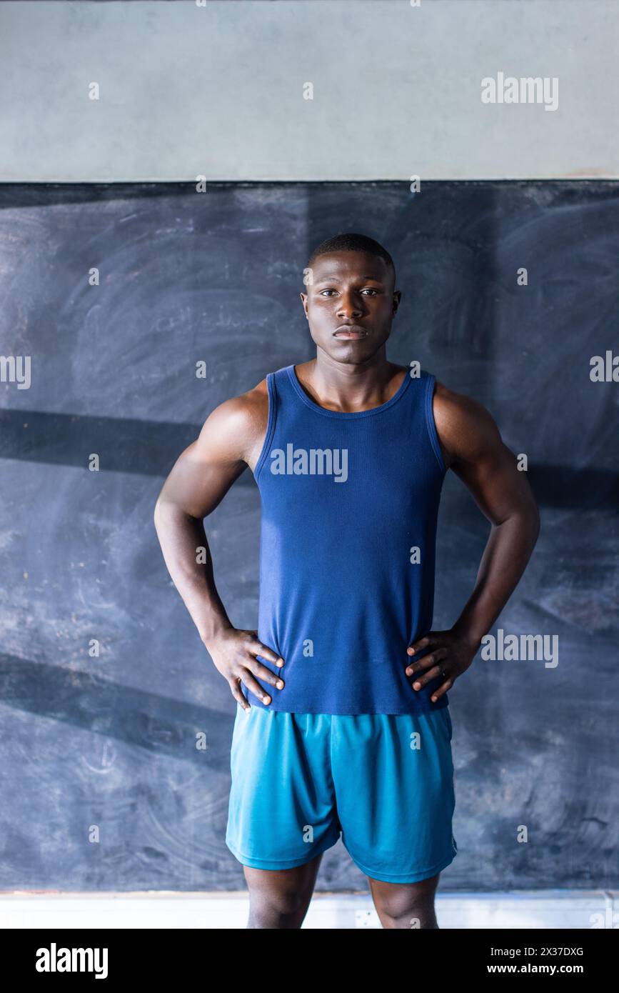Confident African American athlete and fitness model stands in gym ...