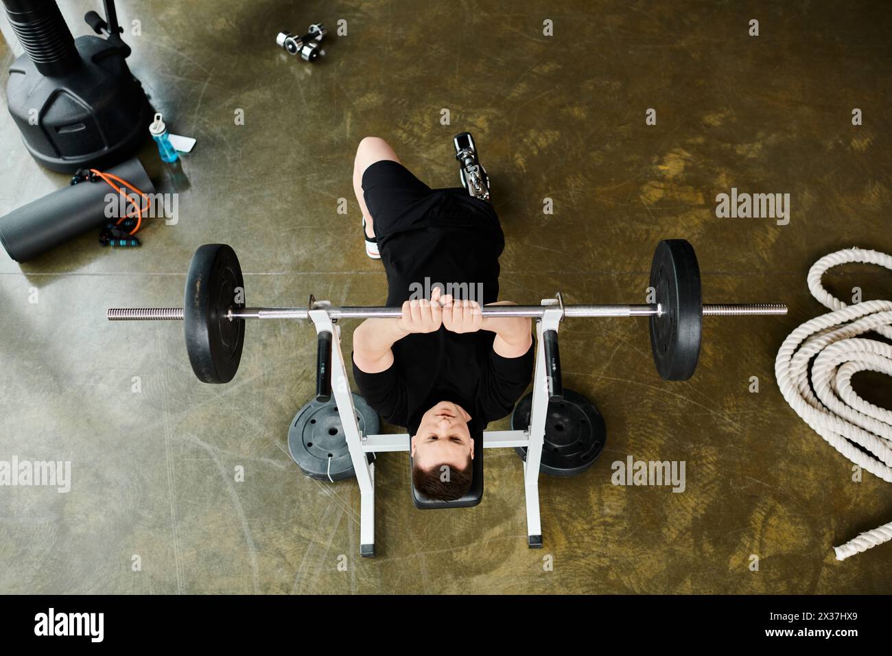 A person with a prosthetic leg is on a bench, lifting a barbell at the ...