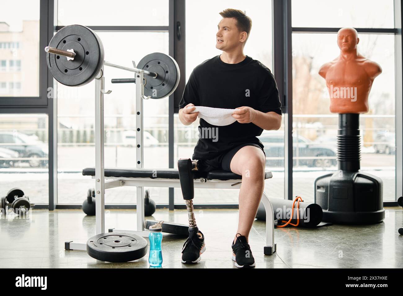 A man with a prosthetic leg sits on a gym bench, deep in thought, as he ...