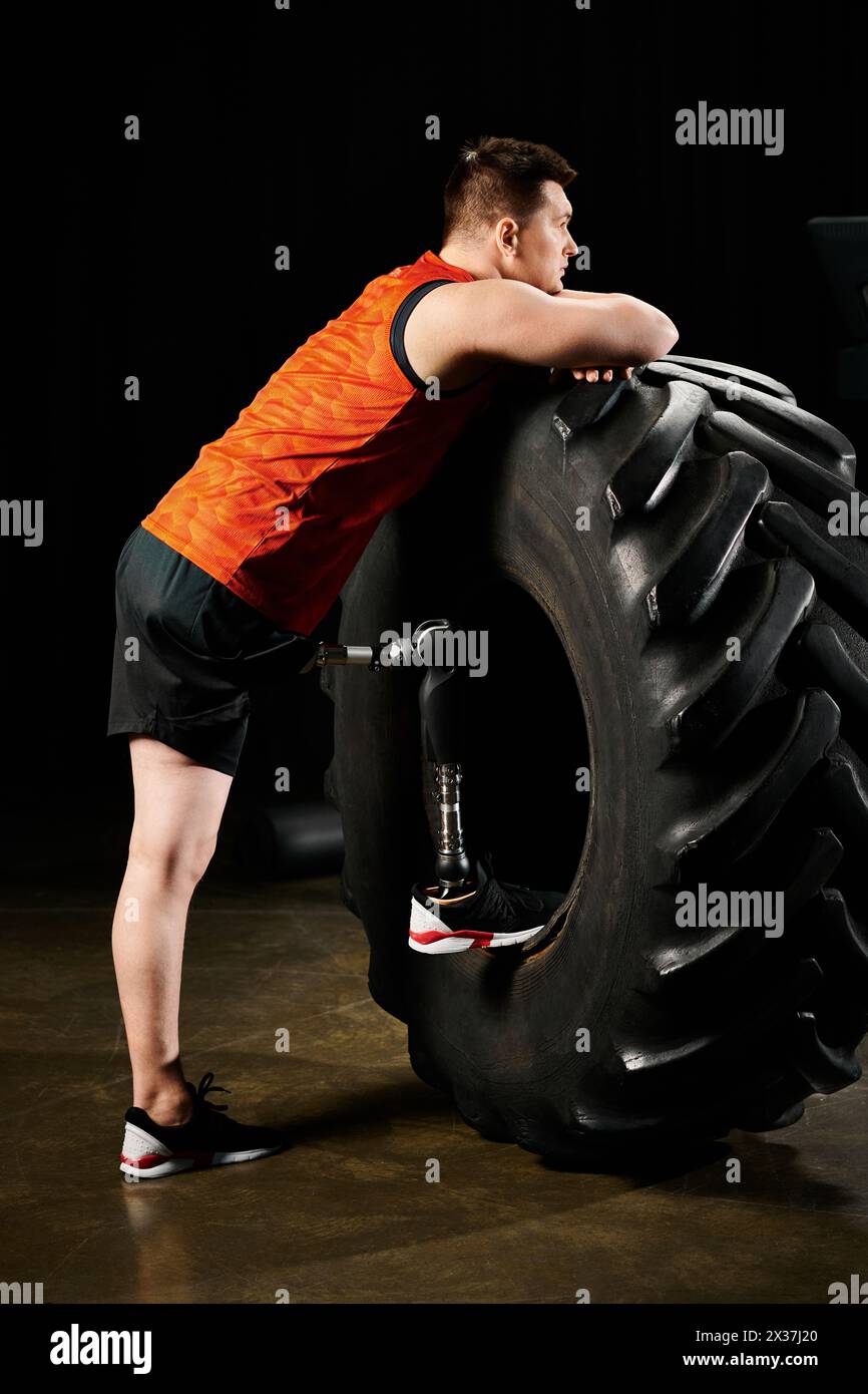 A man with a prosthetic leg stands next to a massive tire, ready to ...