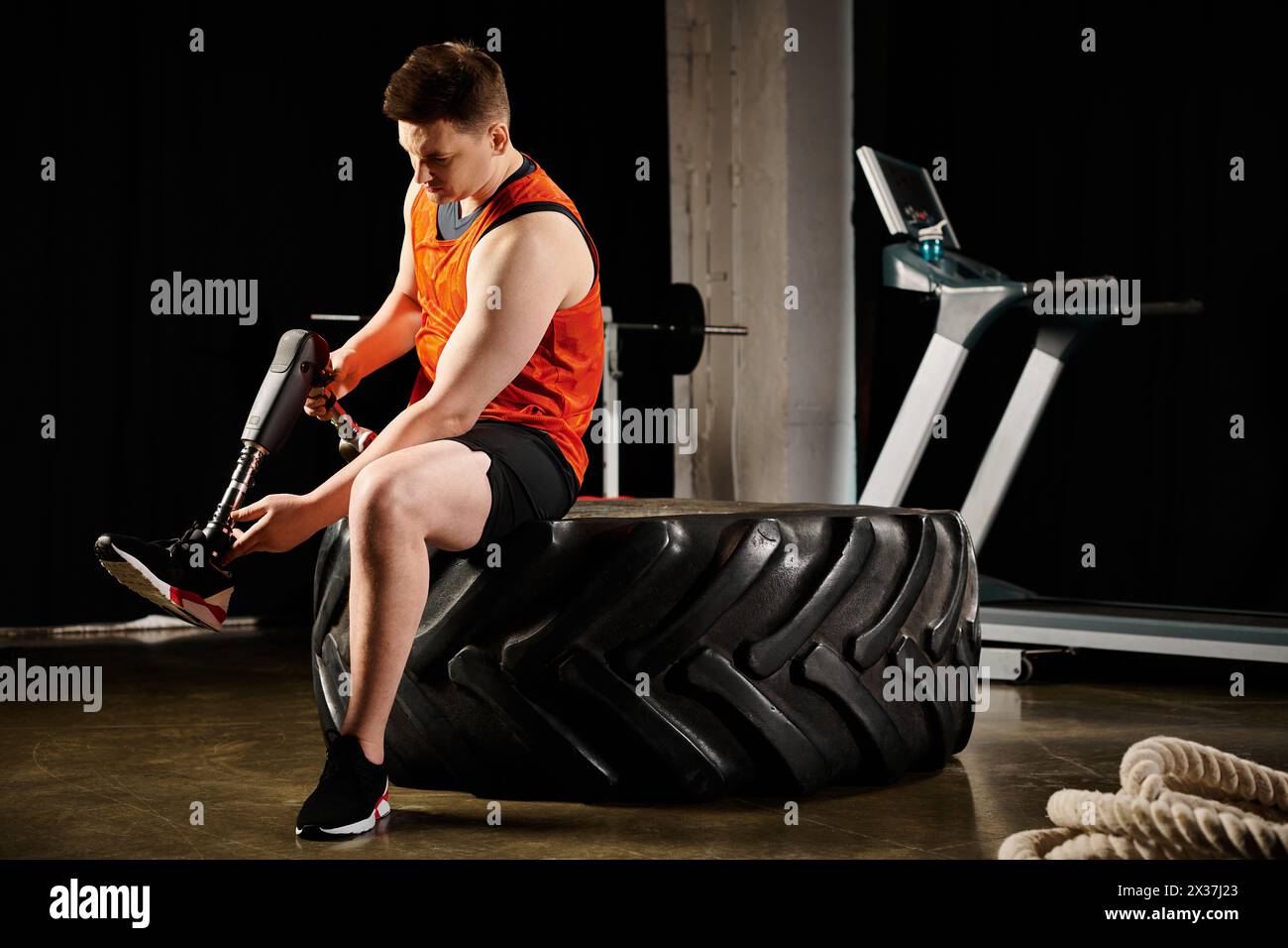 A disabled man with a prosthetic leg sitting confidently on a tire ...
