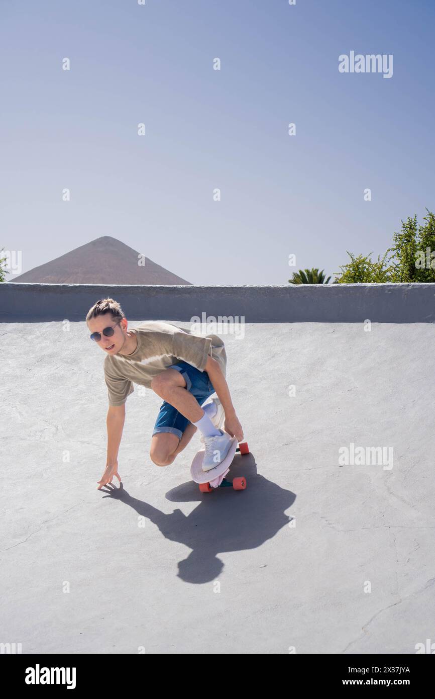 A young man skillfully skateboarding down the ramp on a surf skate ...