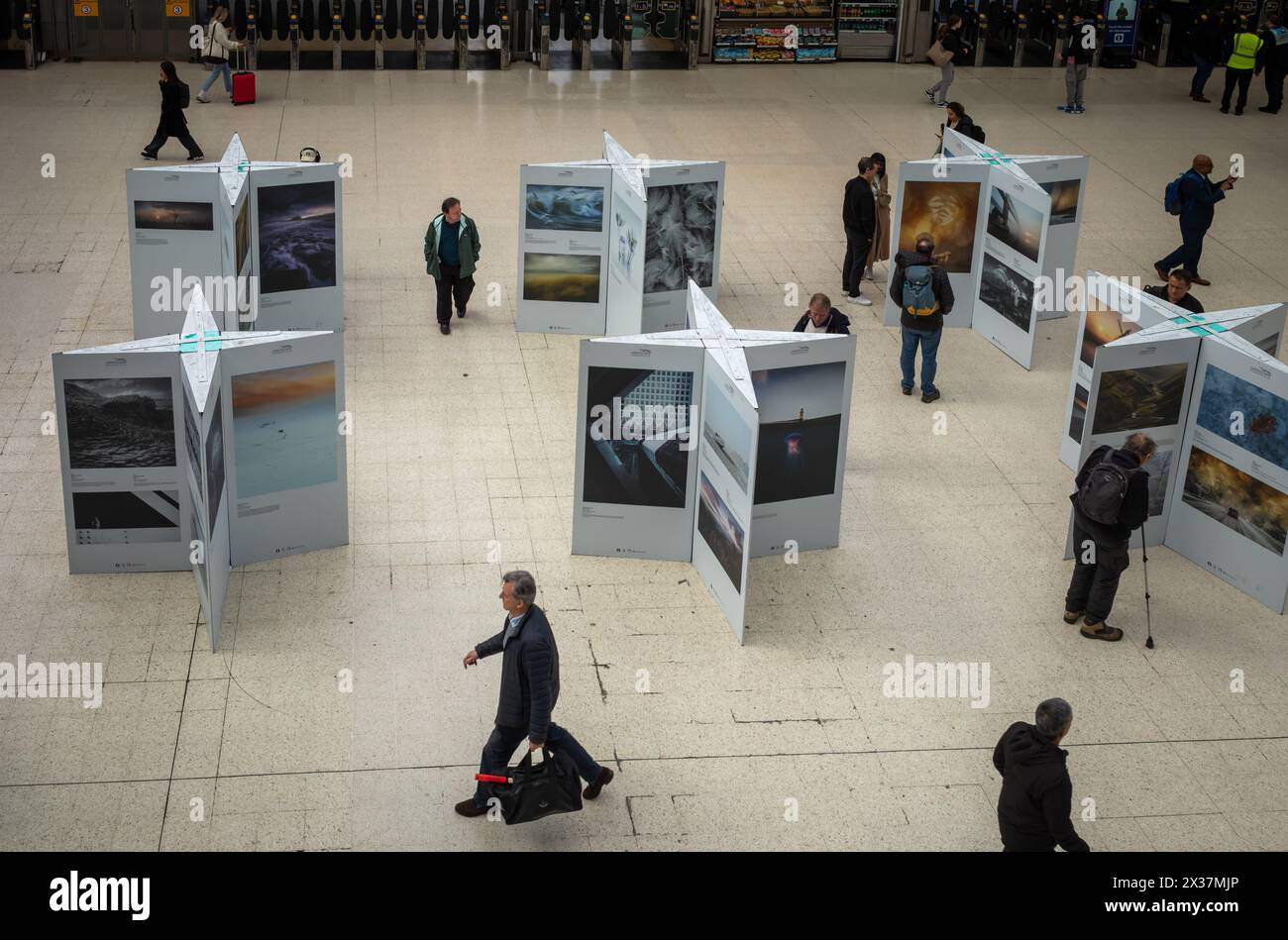 Passengers walk past a photo exhibition on the concourse of Waterloo ...