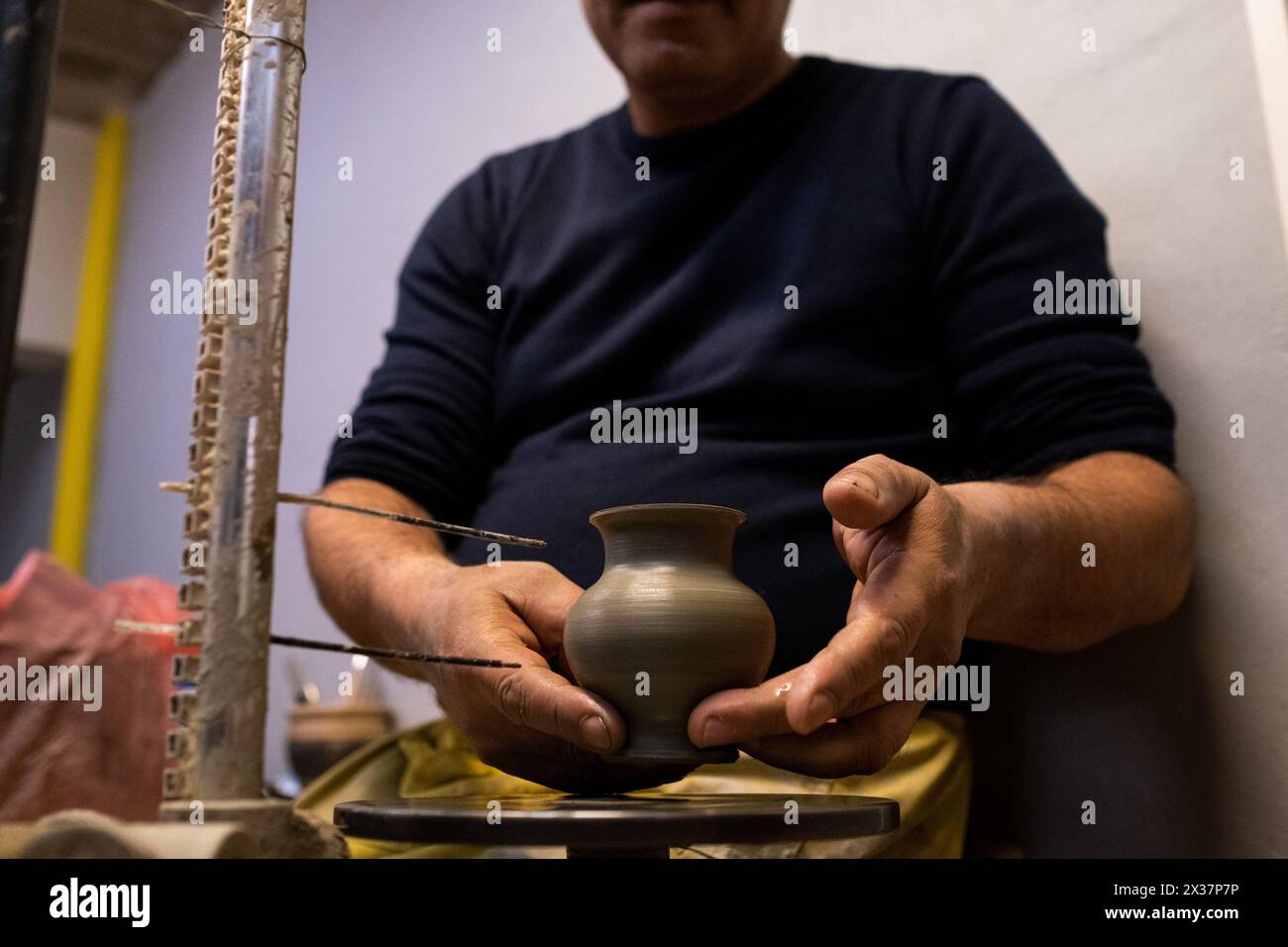 A potter making ceramic pottery inspired by ancient Greek amphorae in ...