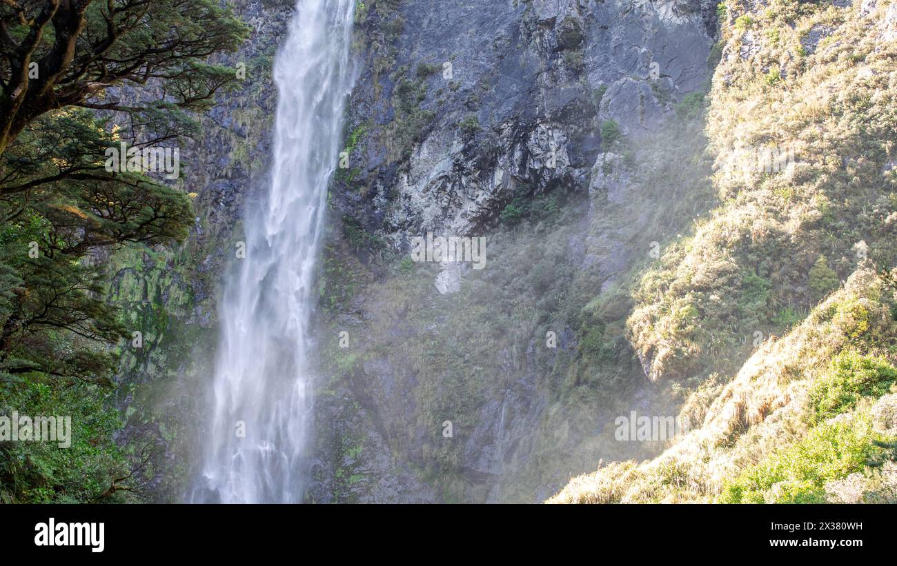 Sunlit waterfall cascades through lush NZ foliage, a serene Arthur's ...