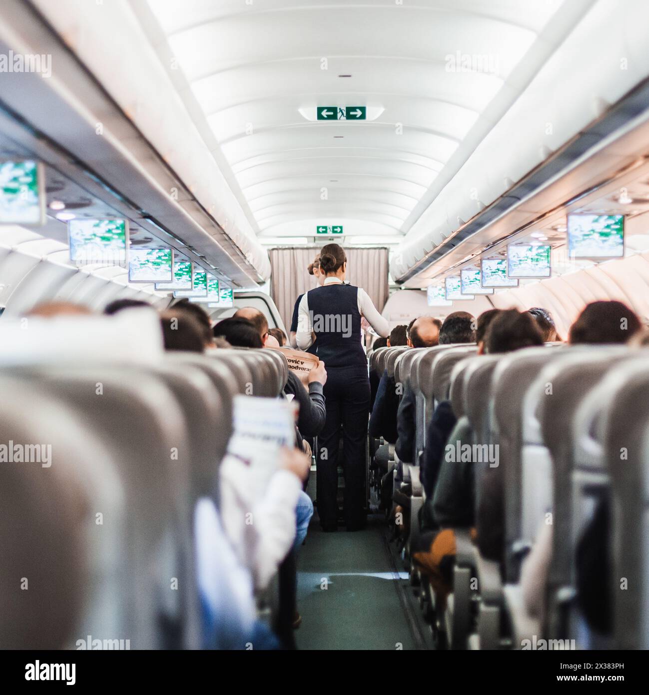 Interior of airplane with passengers on seats and stewardess in uniform ...