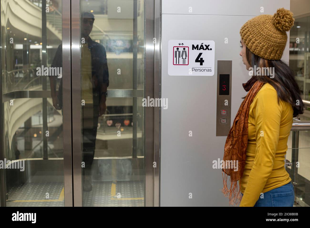 Young Latin American woman in the mall waits for the doors to open to enter the elevator ...