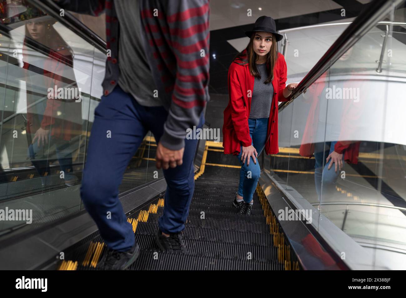 Young Latin American woman (23) walks up the escalator in a shopping ...