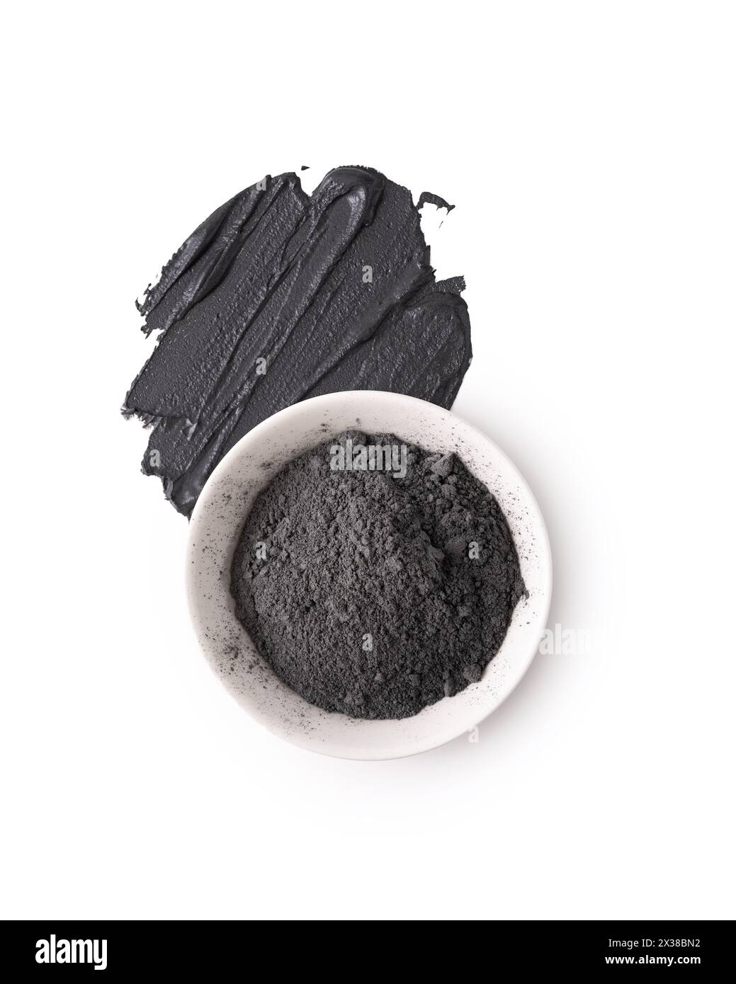 Cosmetic black clay powder in white ceramic bowl with a smear isolated ...