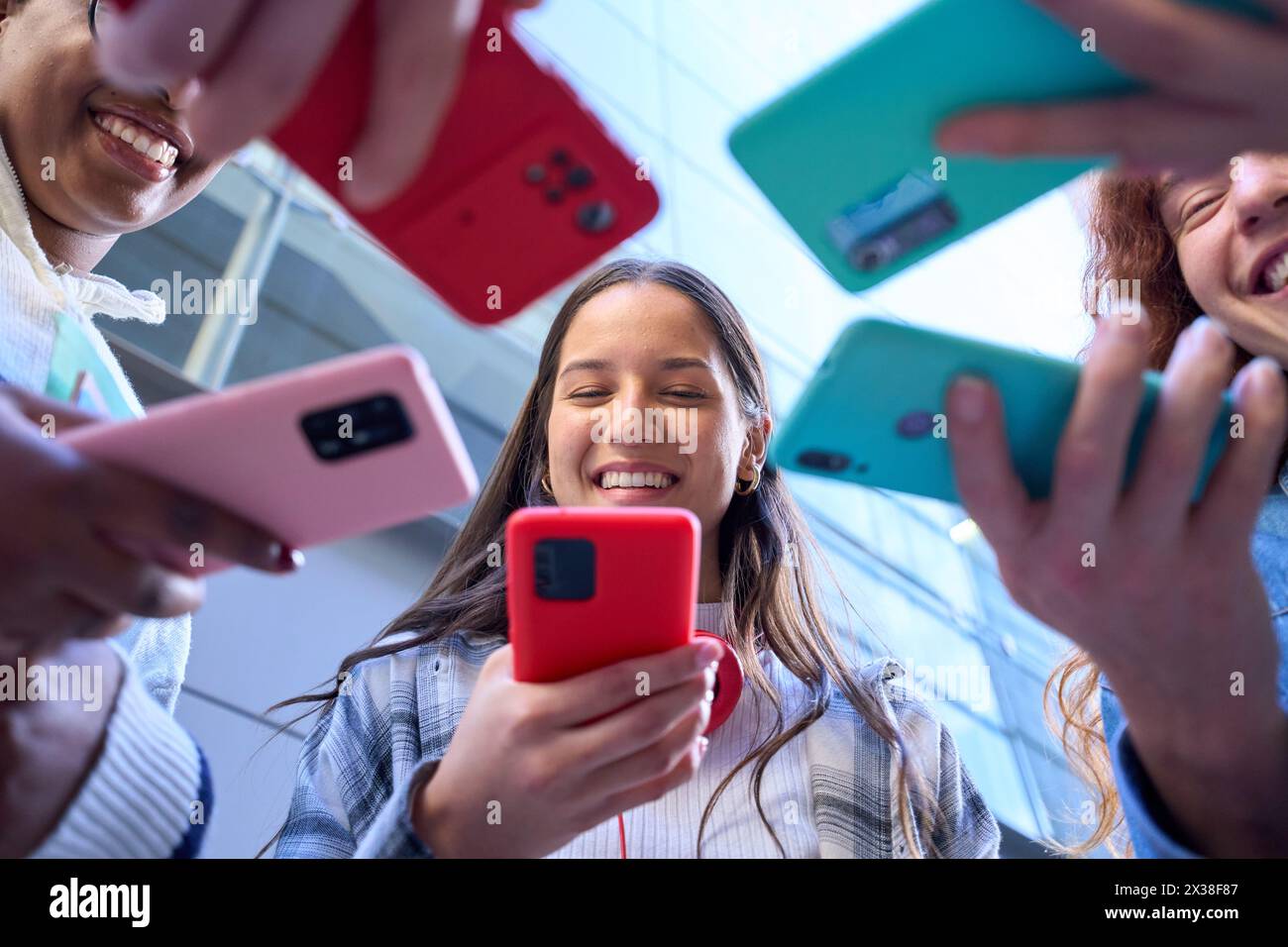 Low angle. Group young smiling people in circle using colorful cell ...
