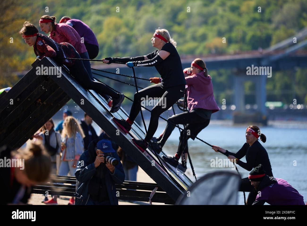 Group of athlete climbing the wooden pyramid wall with rope at the ...