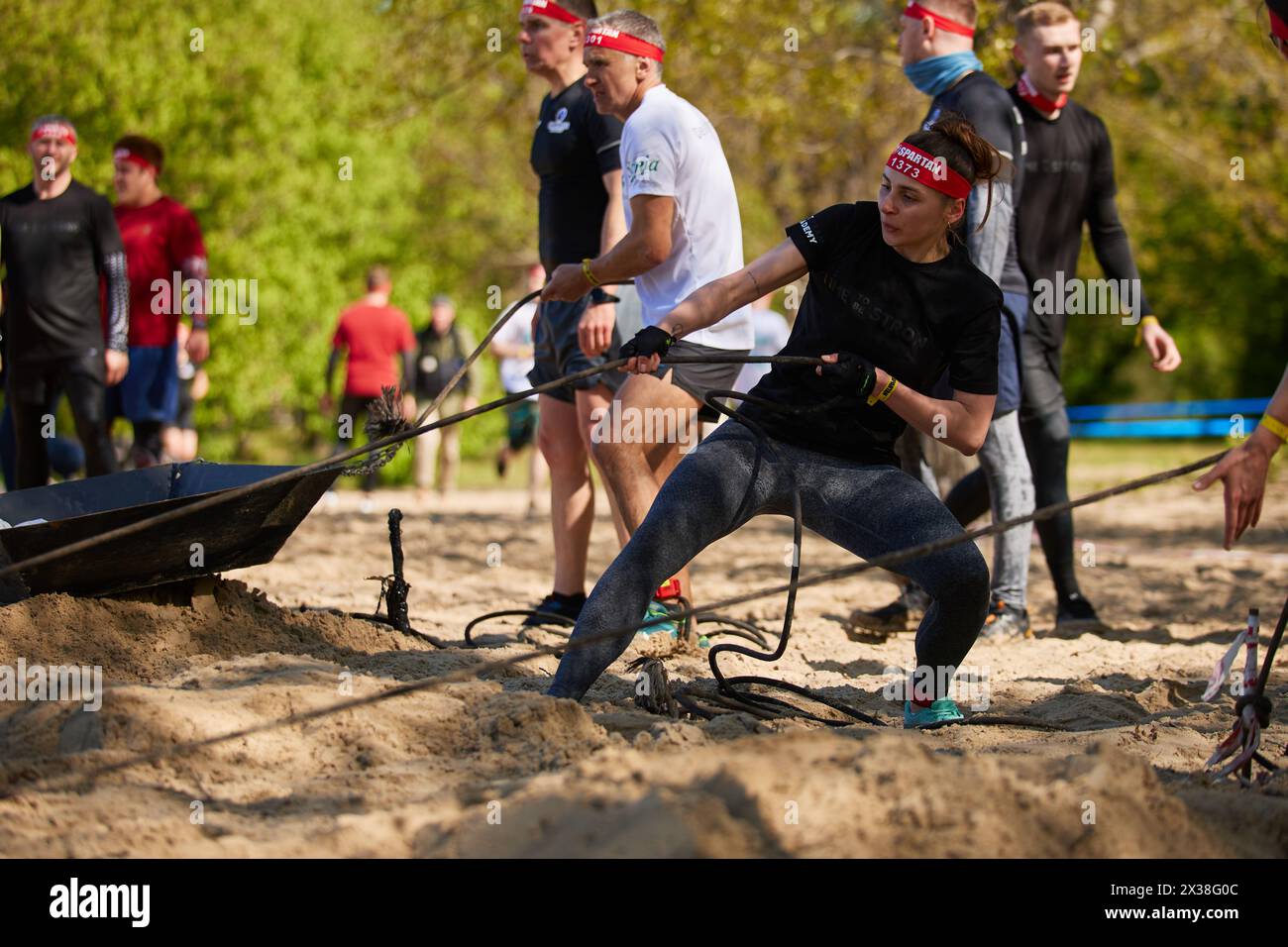 Strong young woman doing the plate drag challenge at the Spartan Race ...