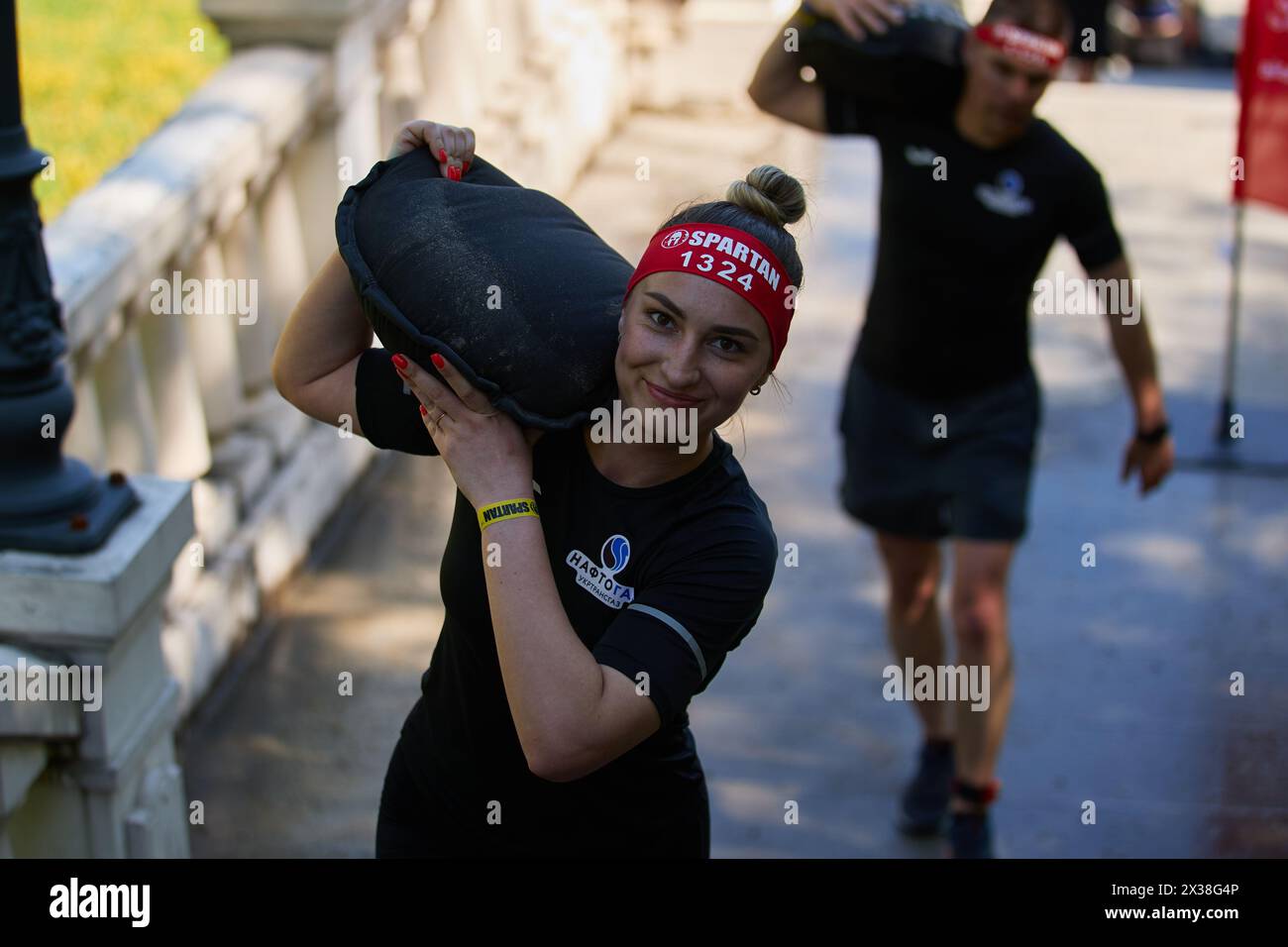 Cheerful Ukrainian female carrying a heavy sand bag at the Spartan Race ...