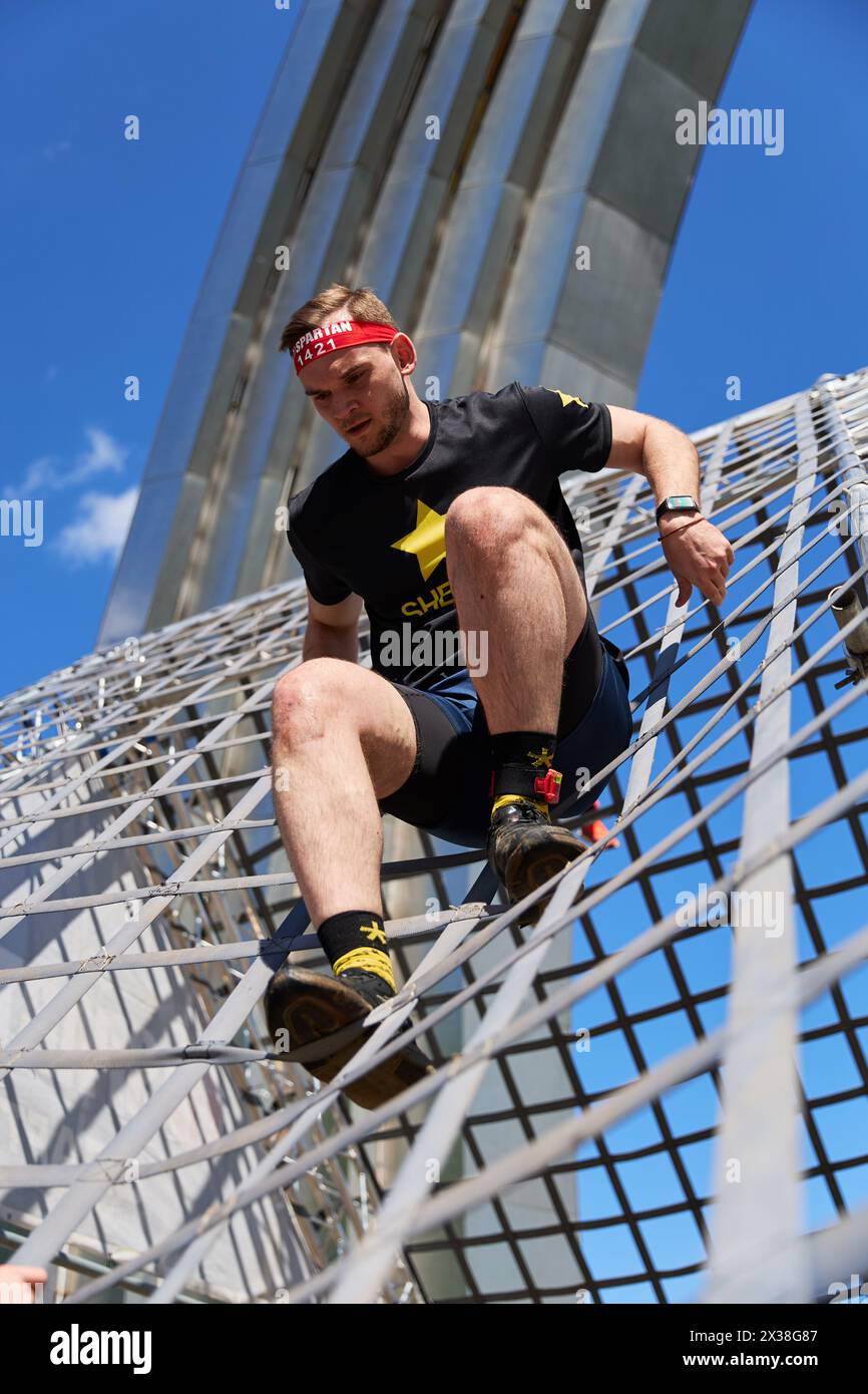 Male athlete climbing down the pyramid at the Spartan Race competition ...