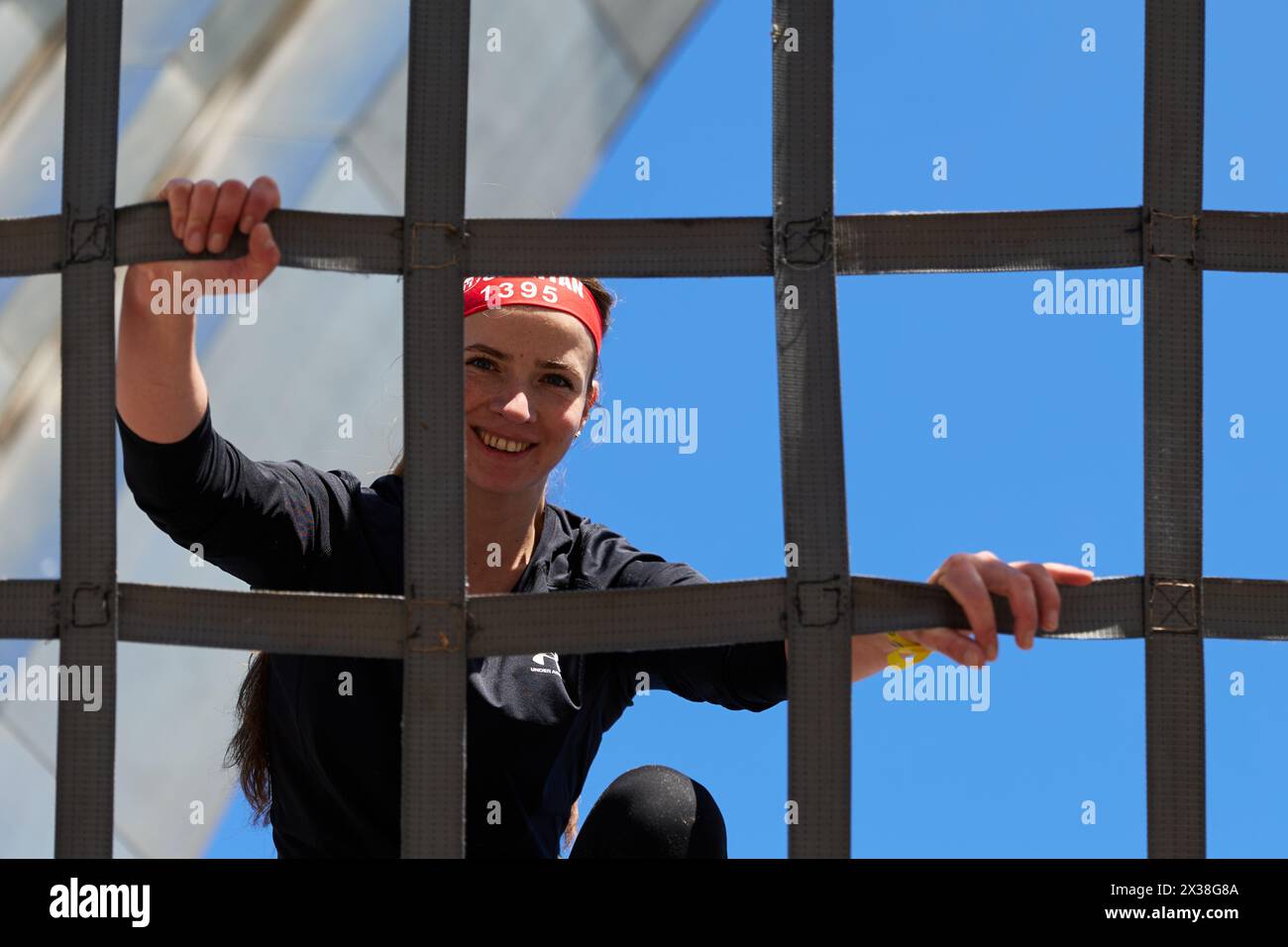 Happy young woman climbing the pyramid at the Spartan Race competition ...