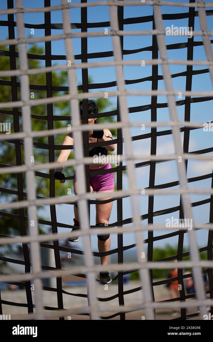 female athlete climbs the obstacle at the Spartan Race competition in ...