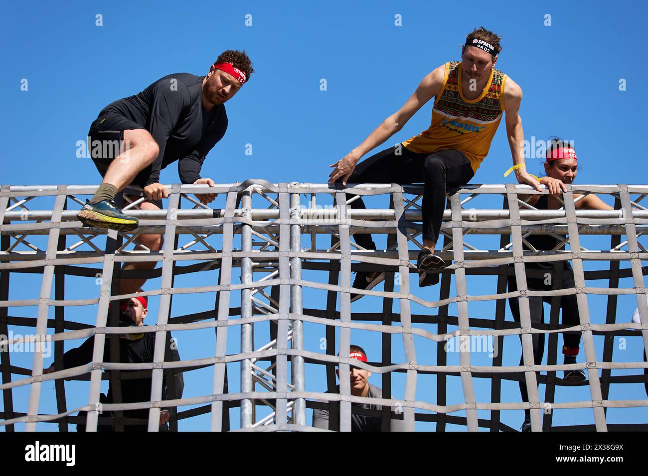 Athletes climbing over the pyramid obstacle at the Spartan Race ...