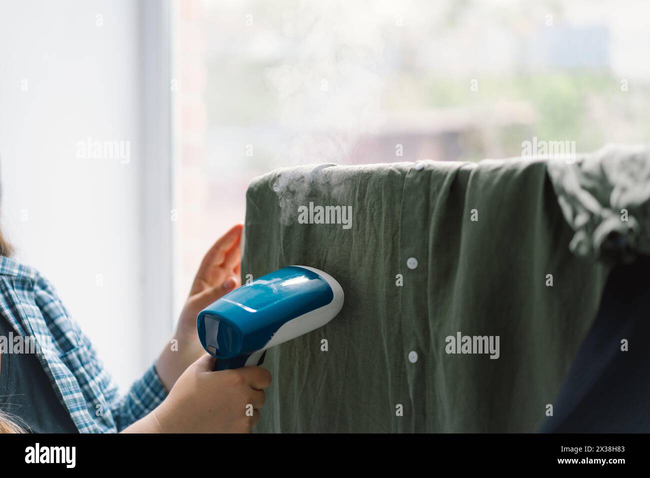 Woman Using Handheld Steamer on a Green Garment at Home During Daytime ...
