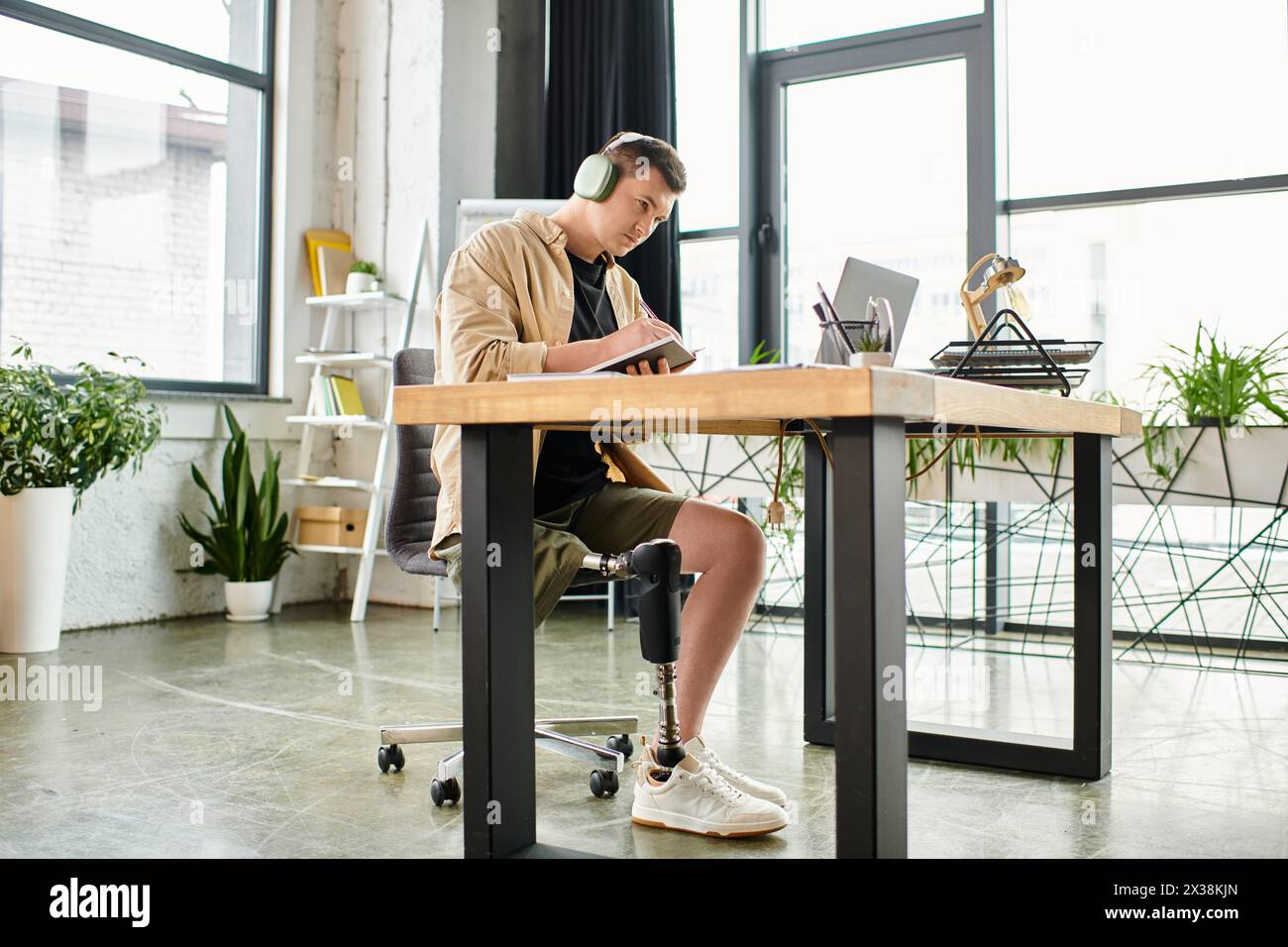 A handsome businessman with a prosthetic leg sits at a desk, focused on ...