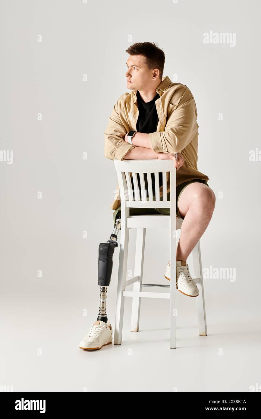 A handsome man with a prosthetic leg poses actively on a white chair ...