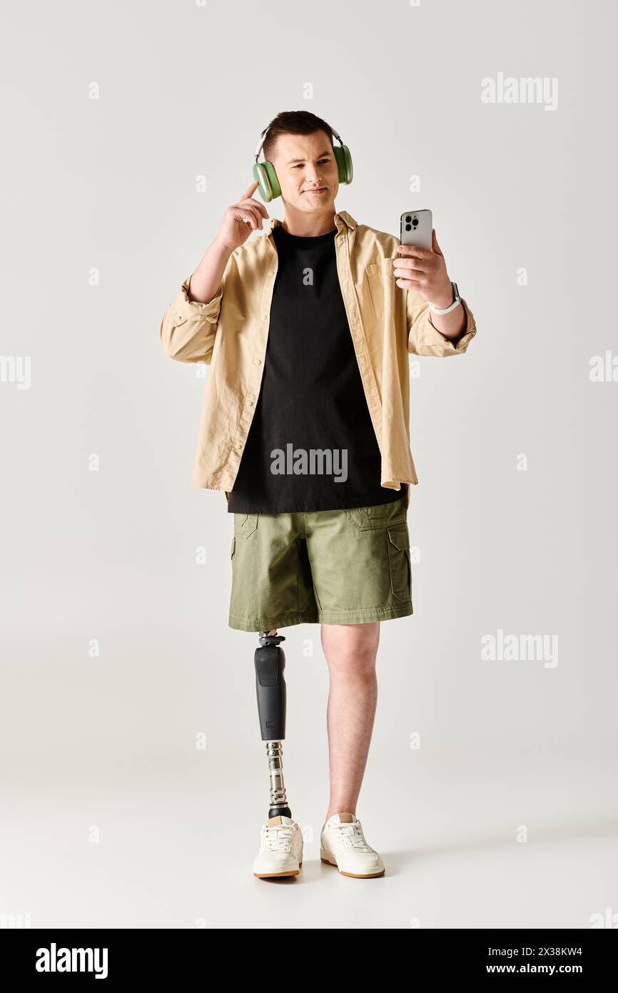 A man with a prosthetic leg wearing headphones and holding a cell phone ...