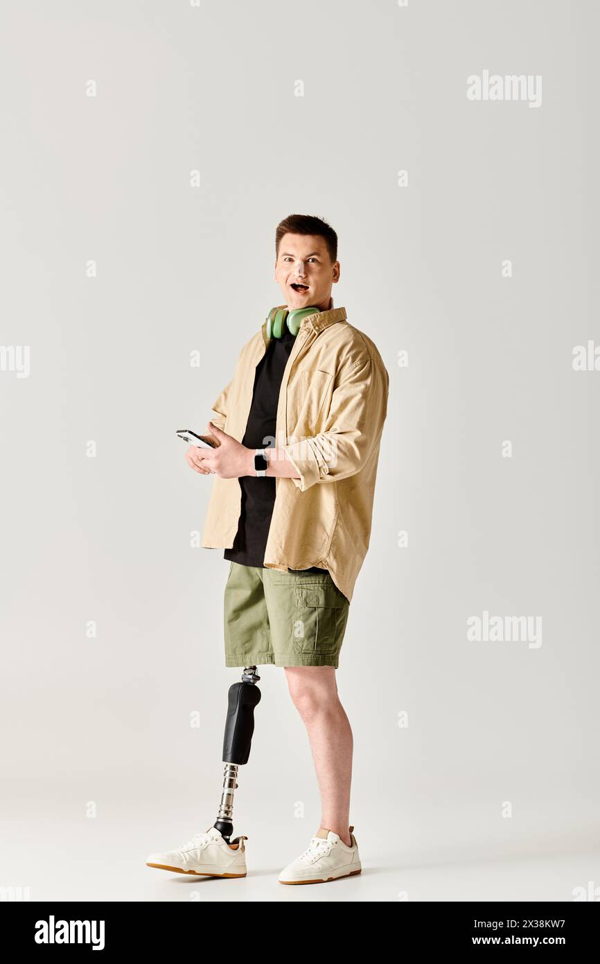 A handsome man with a cast on his leg engaging with his cell phone ...