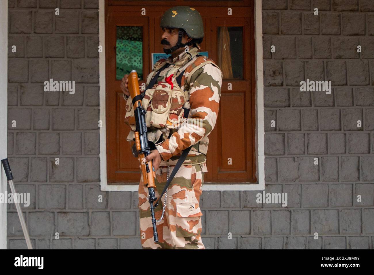 Indian paramilitary trooper stands guard outside a polling station ...