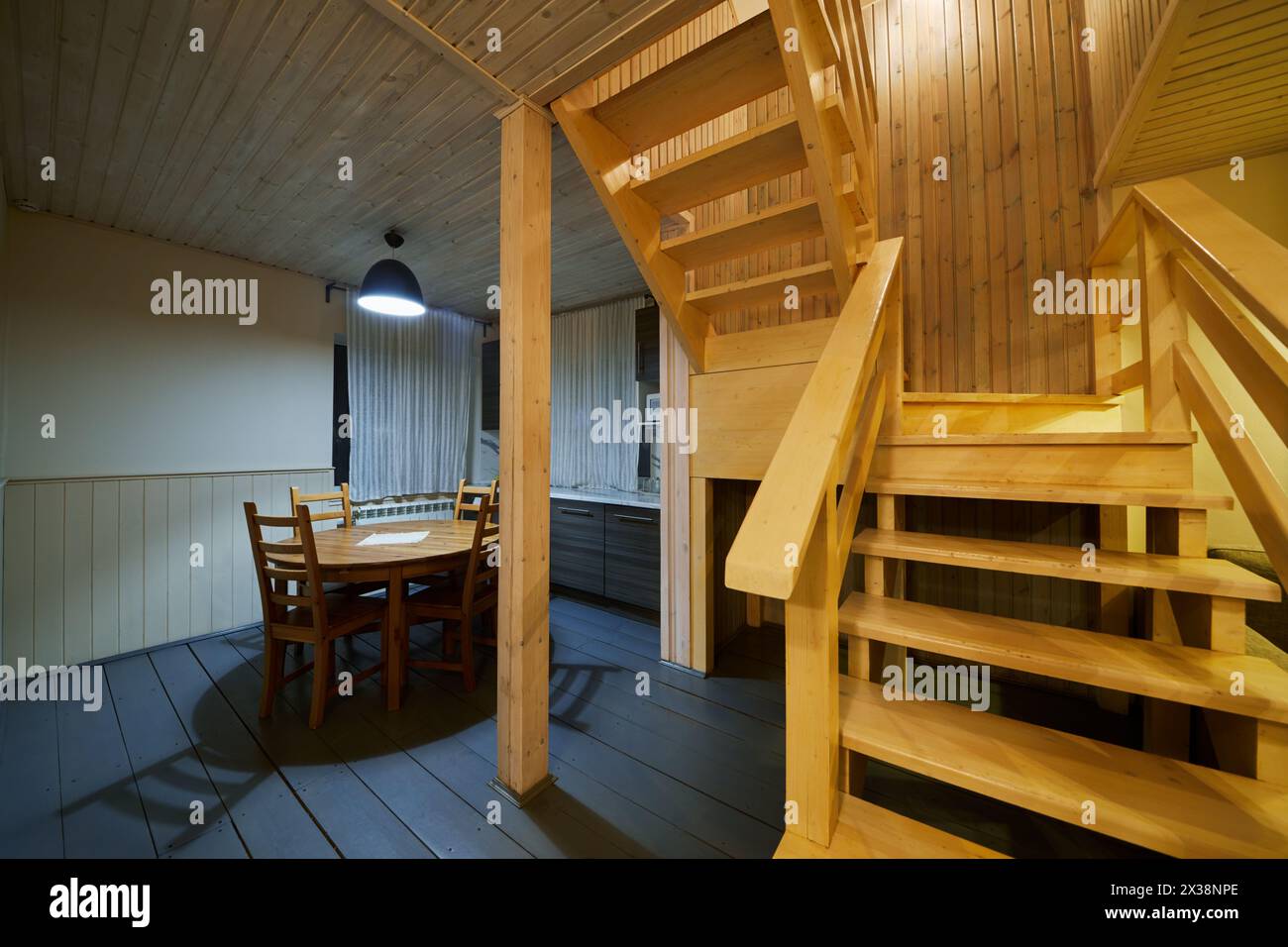 Interior of wooden house, kitchen with table and chairs, stairs to ...