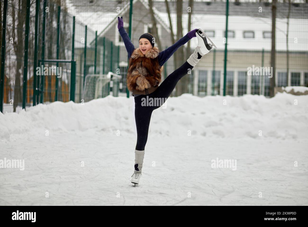 Teenage girl poses doing vertical split during she skates at ice rink ...