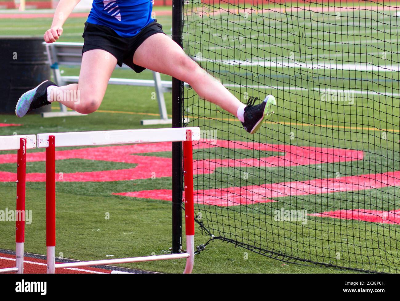 Front view of one high school girl running in a hurdles race outdoor ...