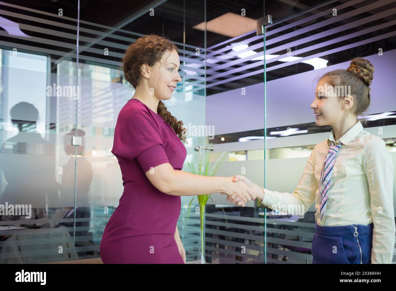 Beautiful woman and girl handshake in modern office with glass walls ...