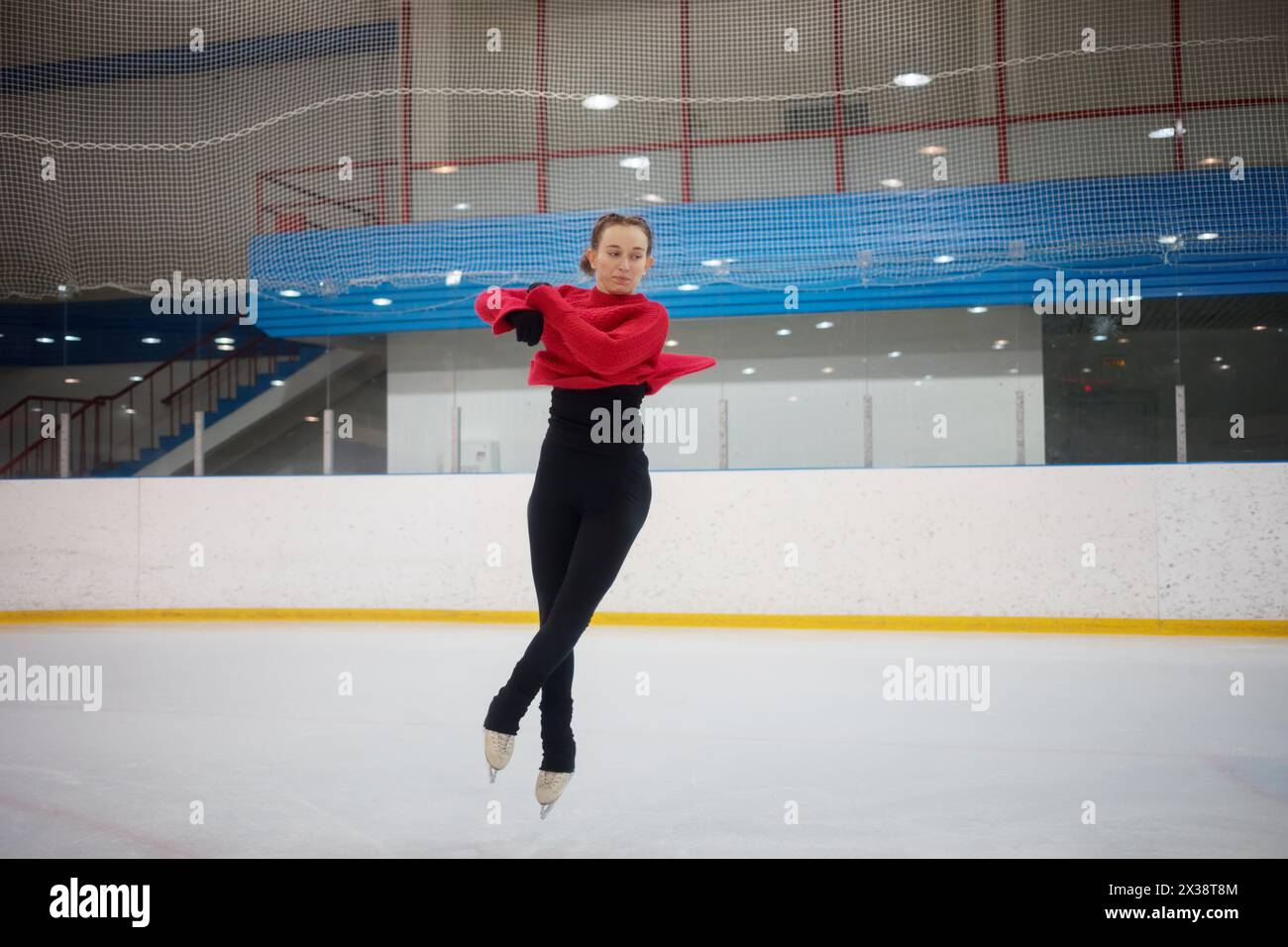 Young slim dancing woman during jump on skate in indoor ice rink Stock ...