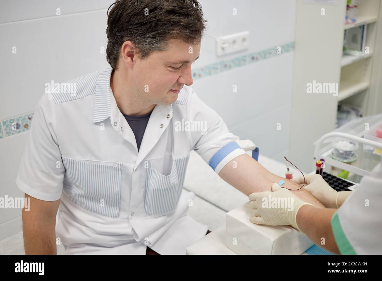 Female medical employee hands hold tube and needle during drawing blood ...