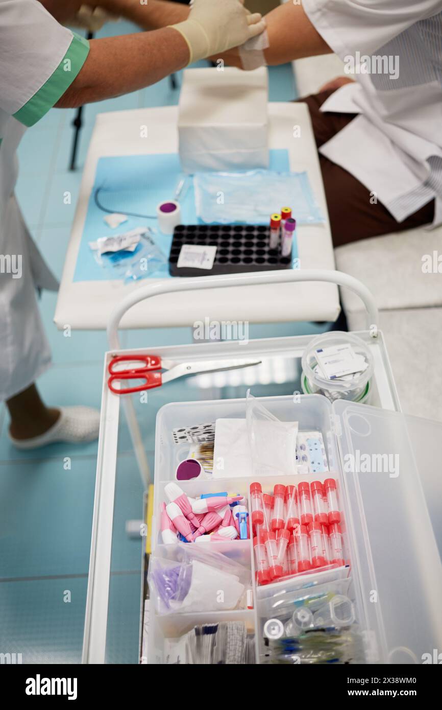Plastic container with blood collection sets on medical table and hands ...