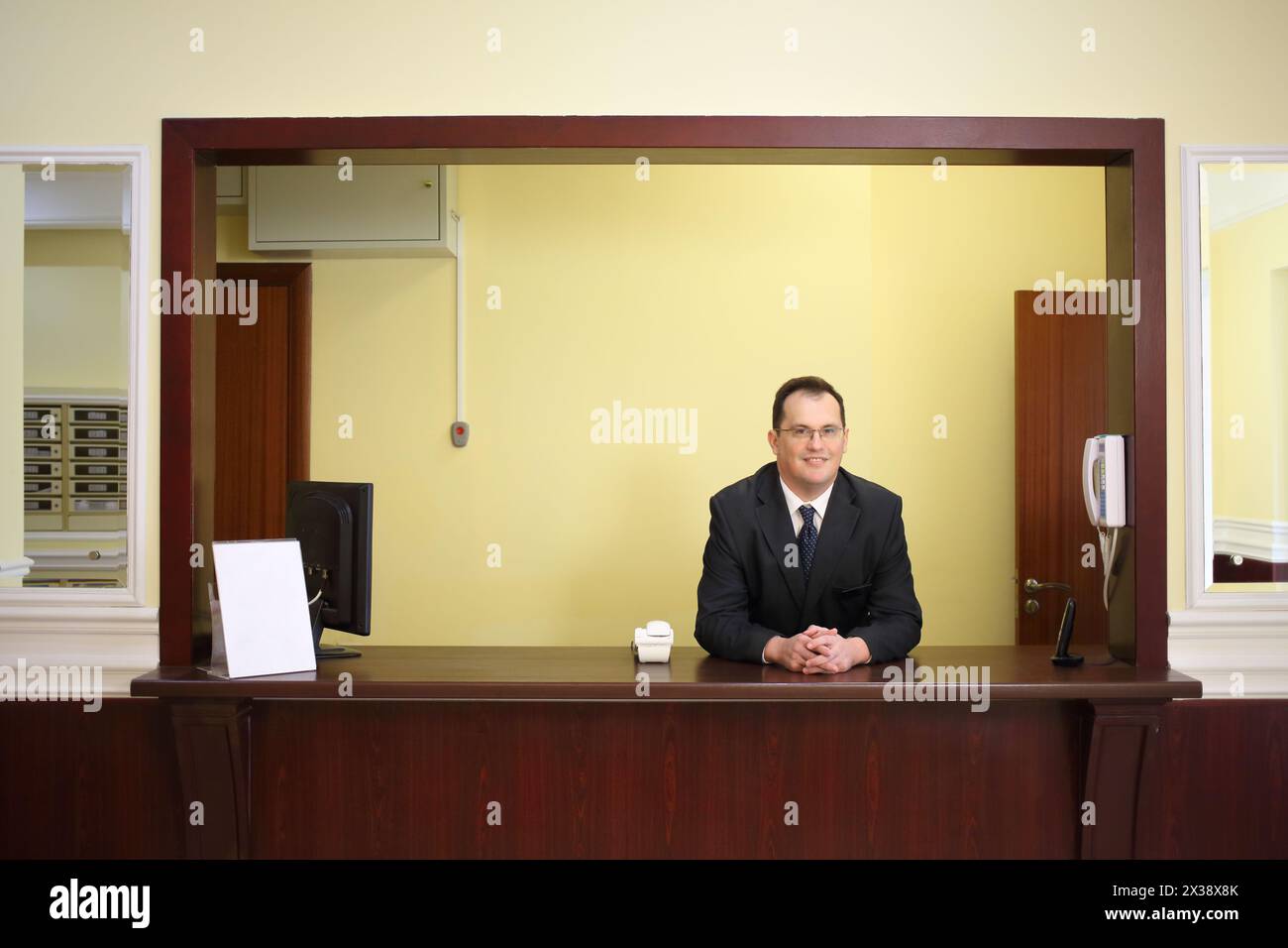 Smiling concierge behind the counter at his workplace in a luxury ...