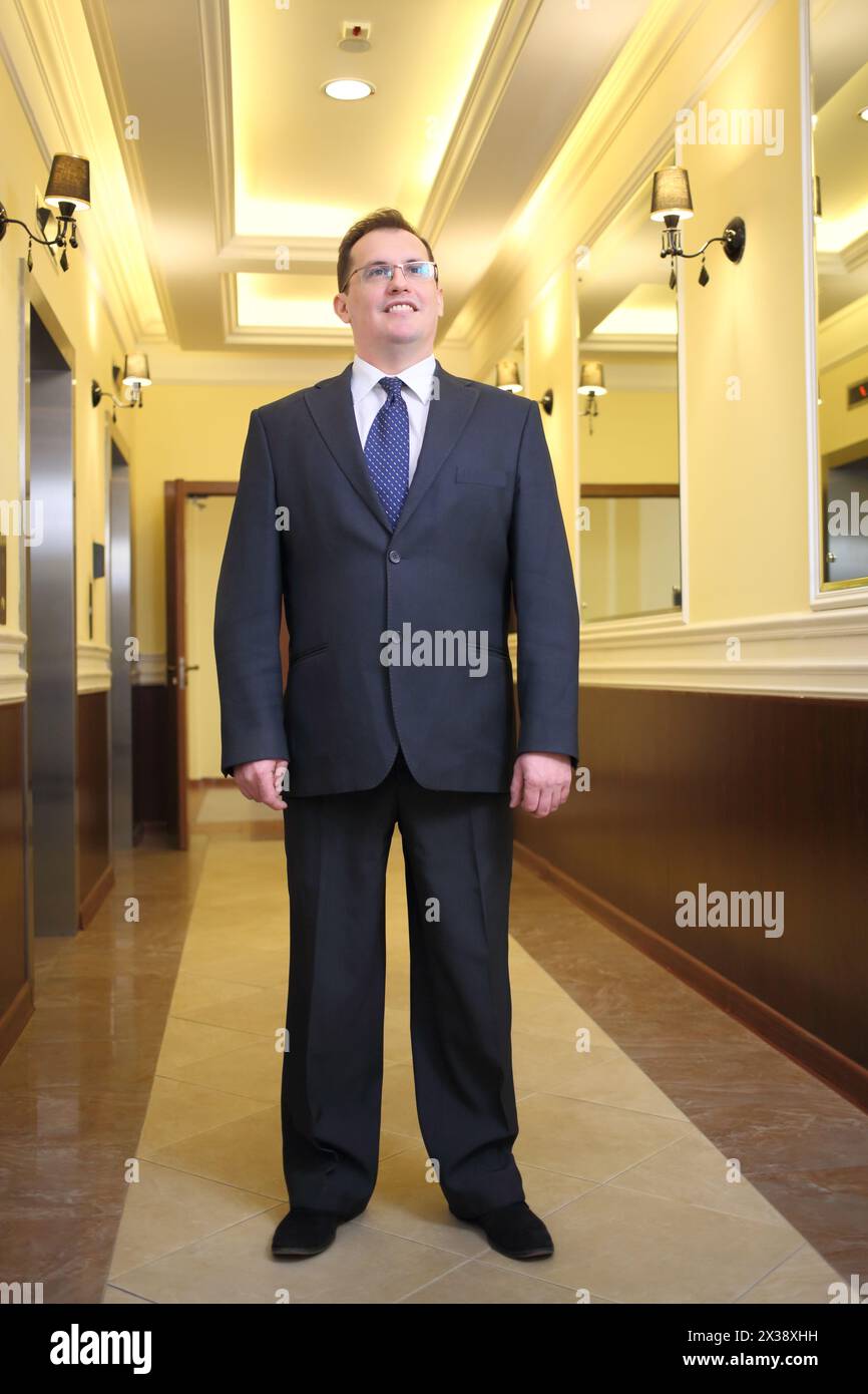 Handsome man in a business suit standing in the hallway between the ...