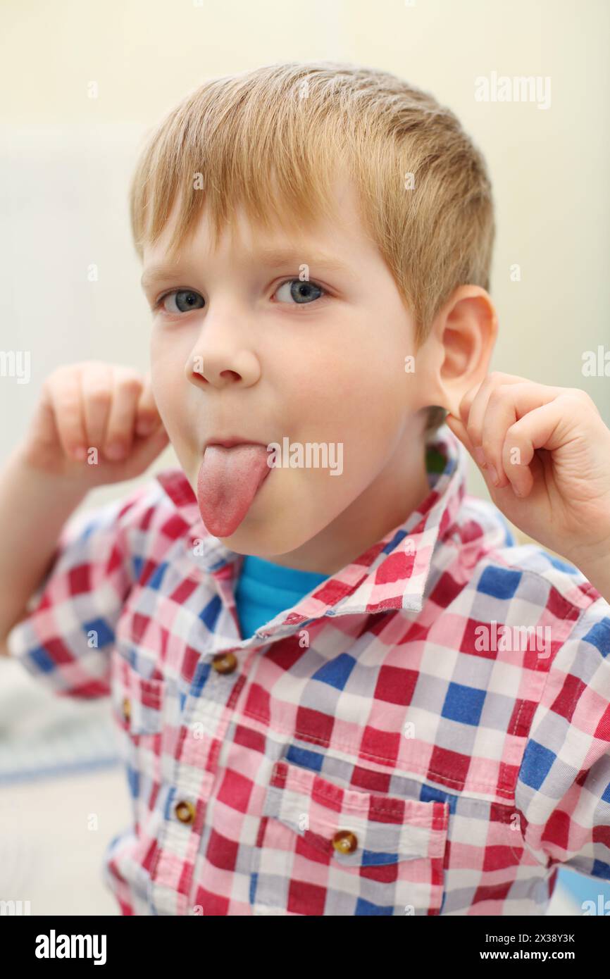 Little handsome blonde boy in checkered shirt grimaces, shallow dof ...