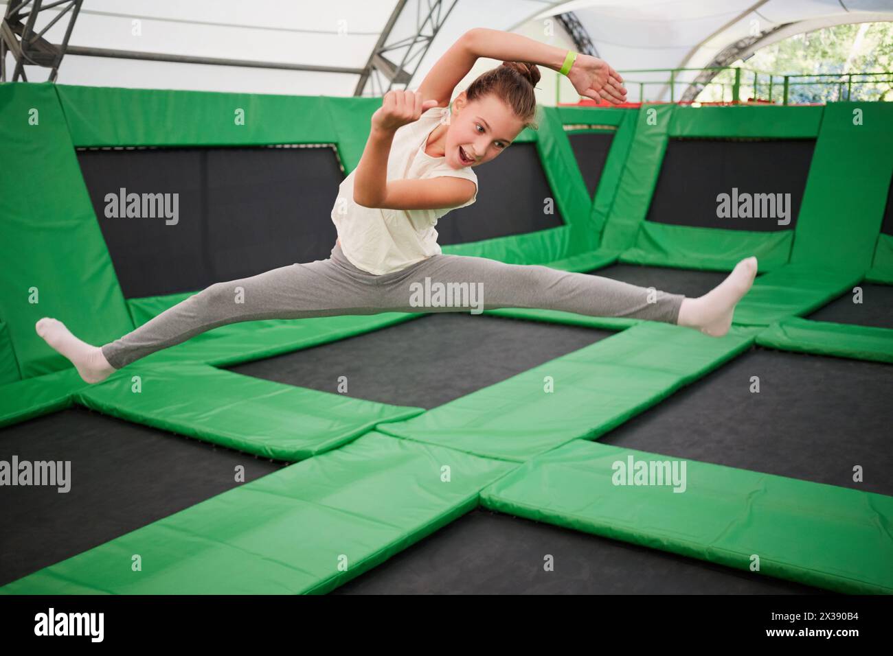 Girl jumps on trampoline attraction making leg-split Stock Photo - Alamy