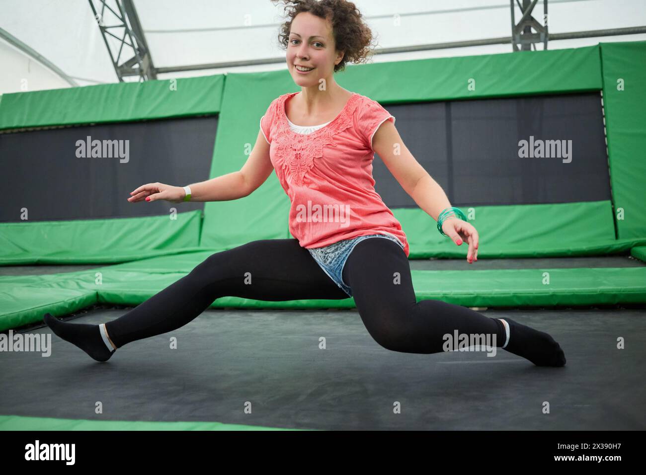 Young woman jumps on trampoline attraction in sitting position Stock ...