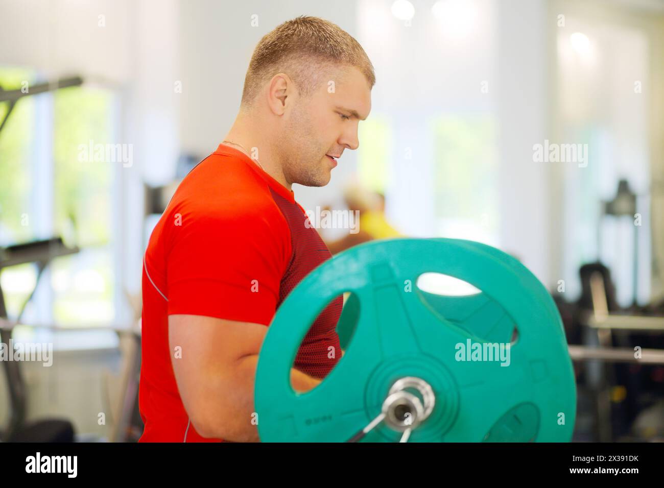 Strong man lifts barbell in modern gym with fitness equipment Stock ...