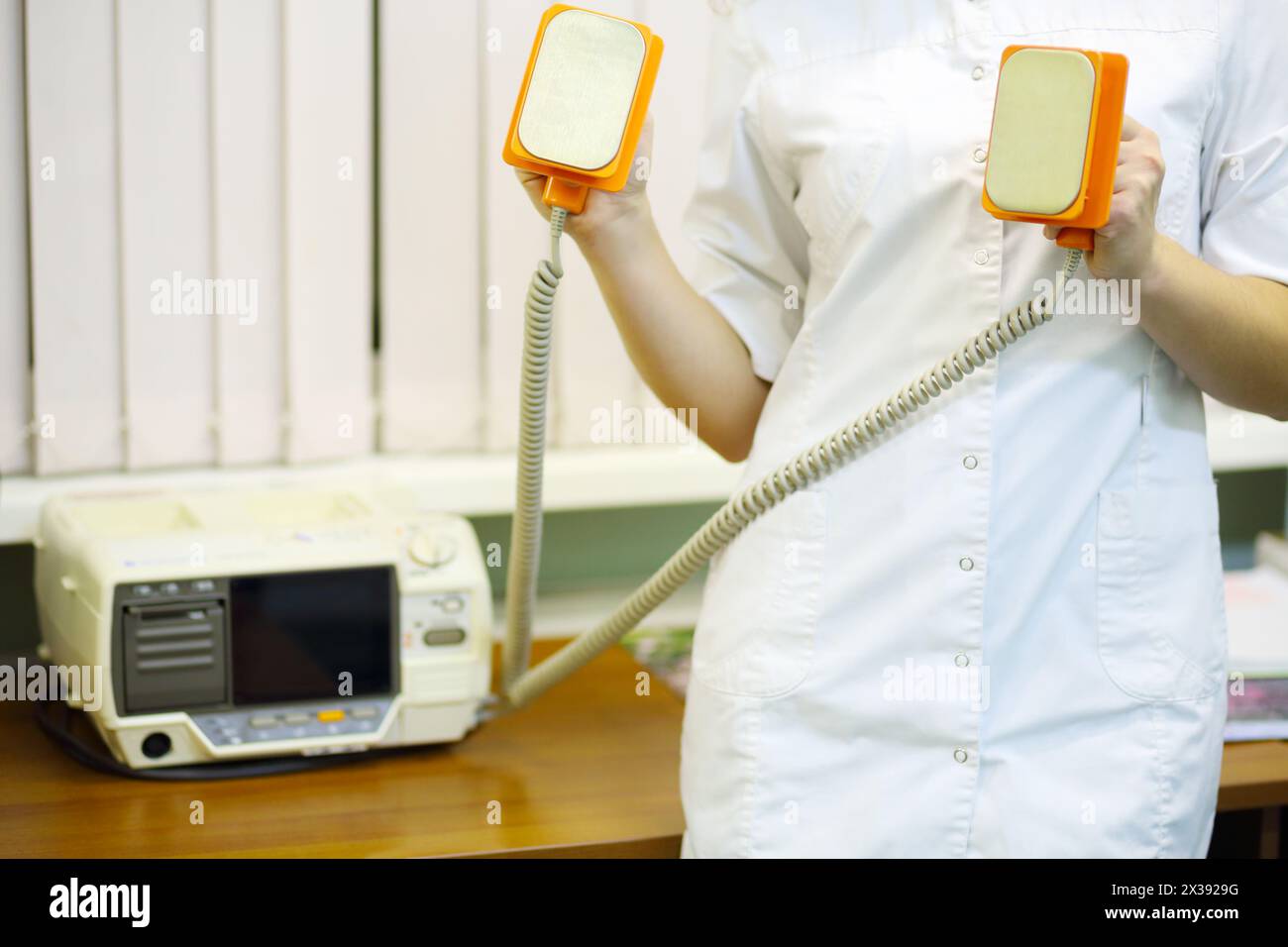 Doctor in white holds electroshock probes in hospital cabinet, noface ...